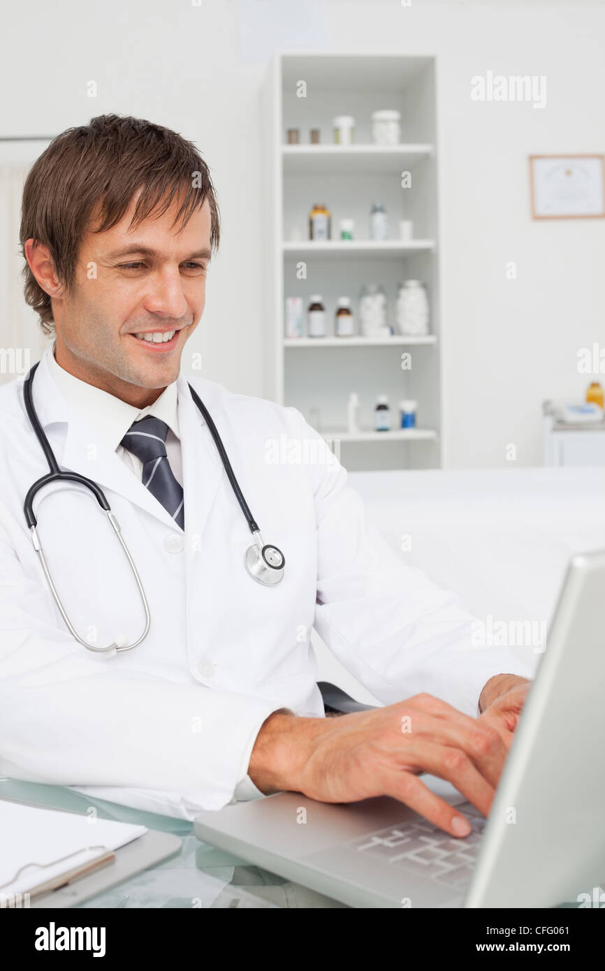 Smiling practitioner typing on his laptop Stock Photo - Alamy