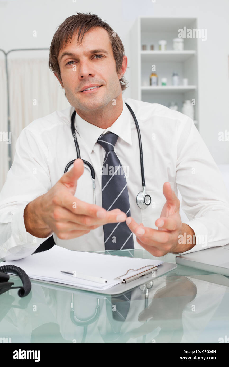 Relaxed doctor looking at the camera while giving explanations Stock ...