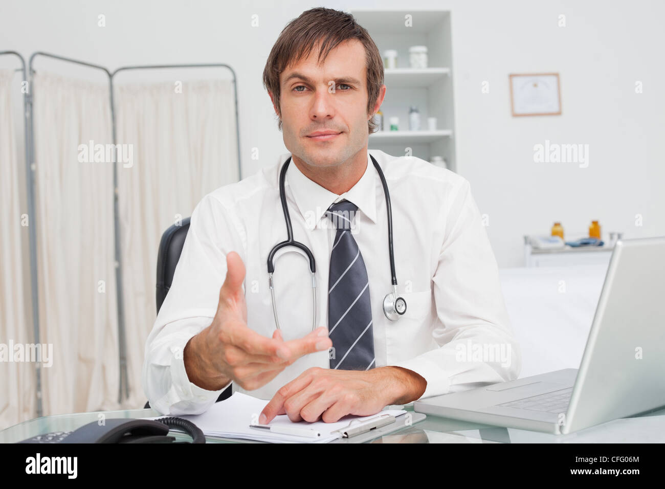 Serious doctor looking at the camera while offering a hand Stock Photo ...