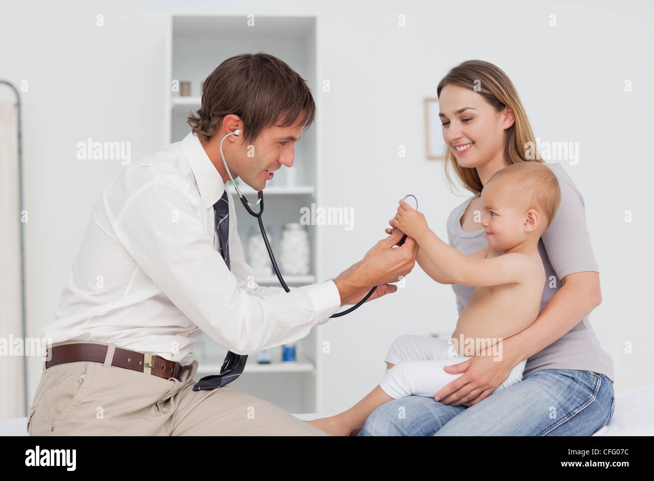 Little baby playing with a stethoscope while being held by her mother ...