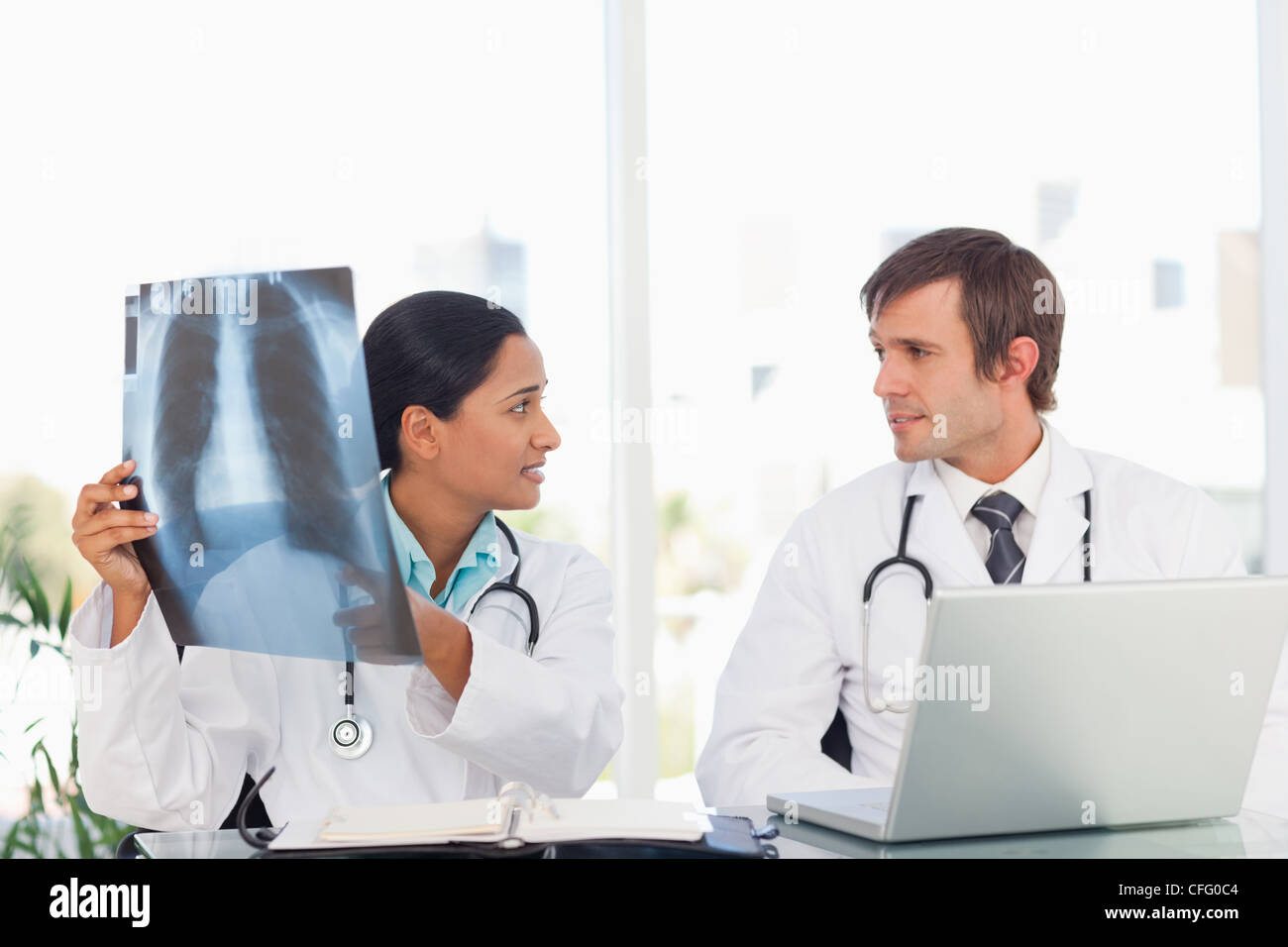 Serious doctor explaining a problem on the x-ray to her colleague Stock ...