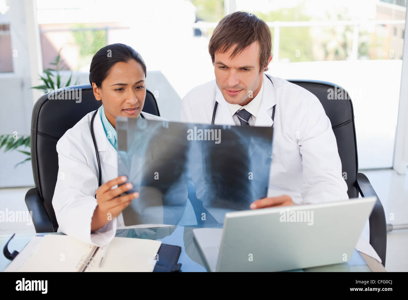Serious doctors looking at a chest x-ray while sitting at a desk Stock ...