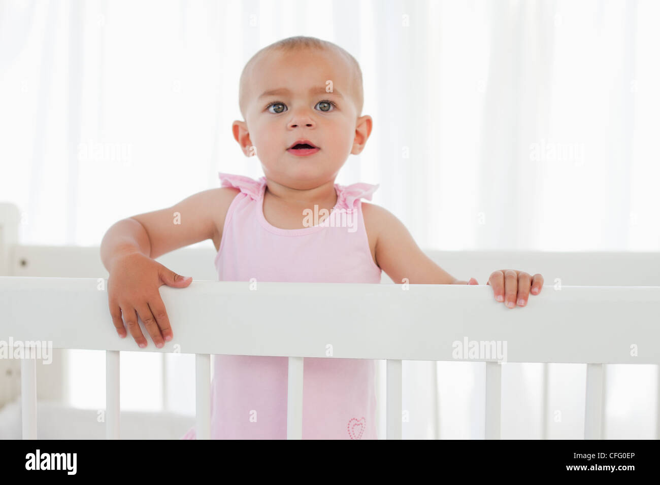 Beautiful baby standing up in her bed Stock Photo - Alamy