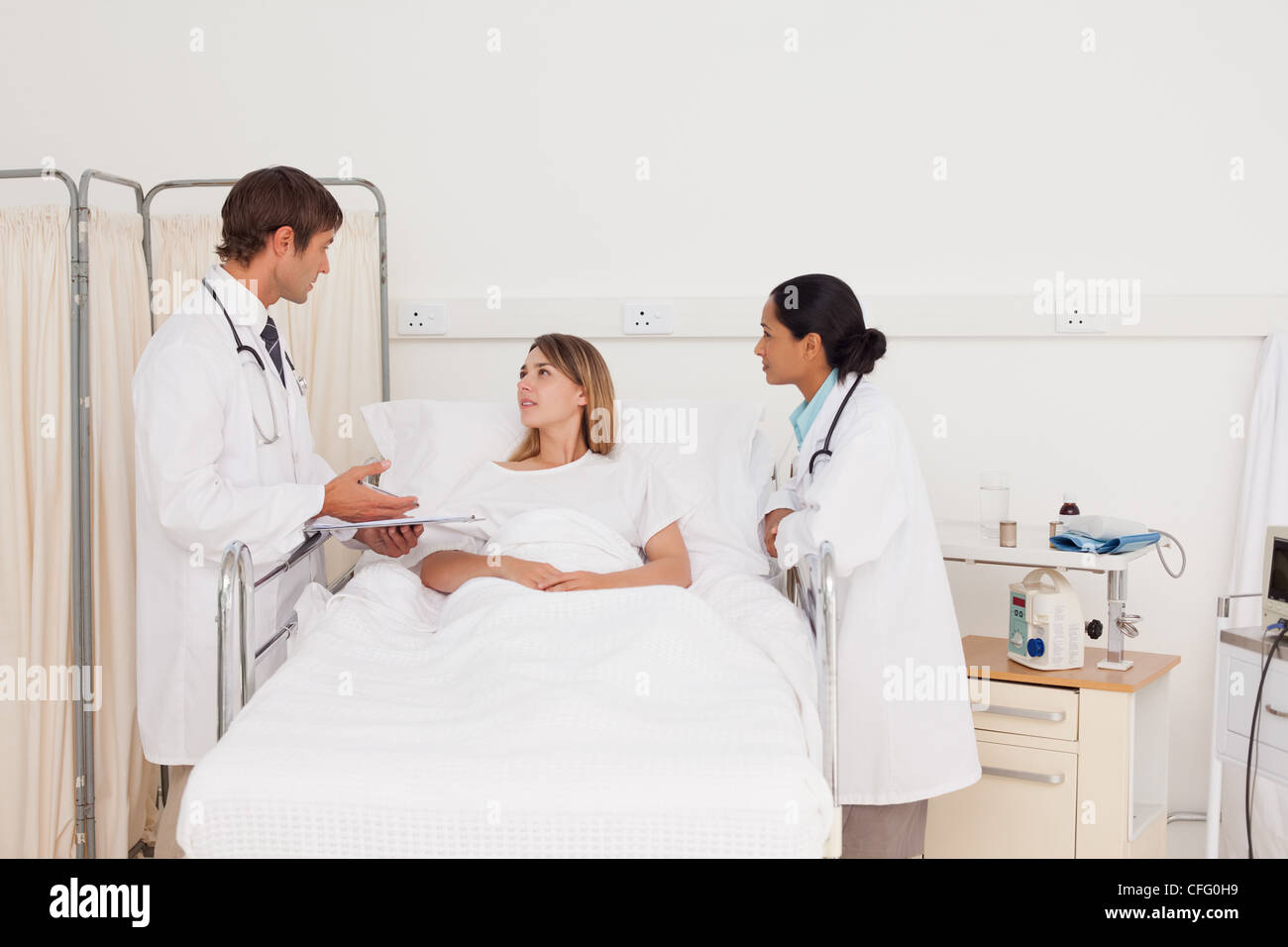 Serious doctor talking to his patient while standing in a hospital room ...