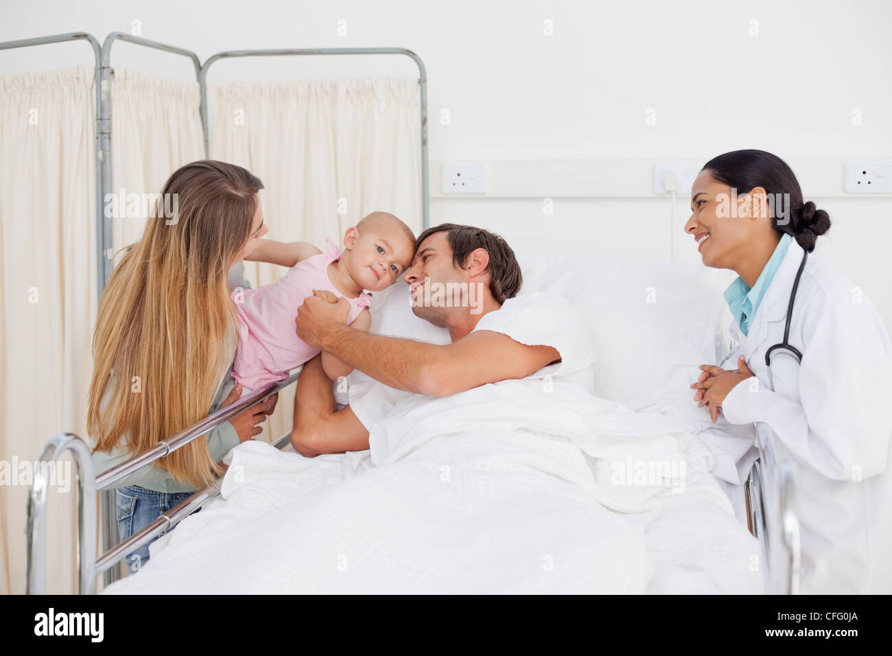 Little baby and her father hugging while a doctor is looking at them ...