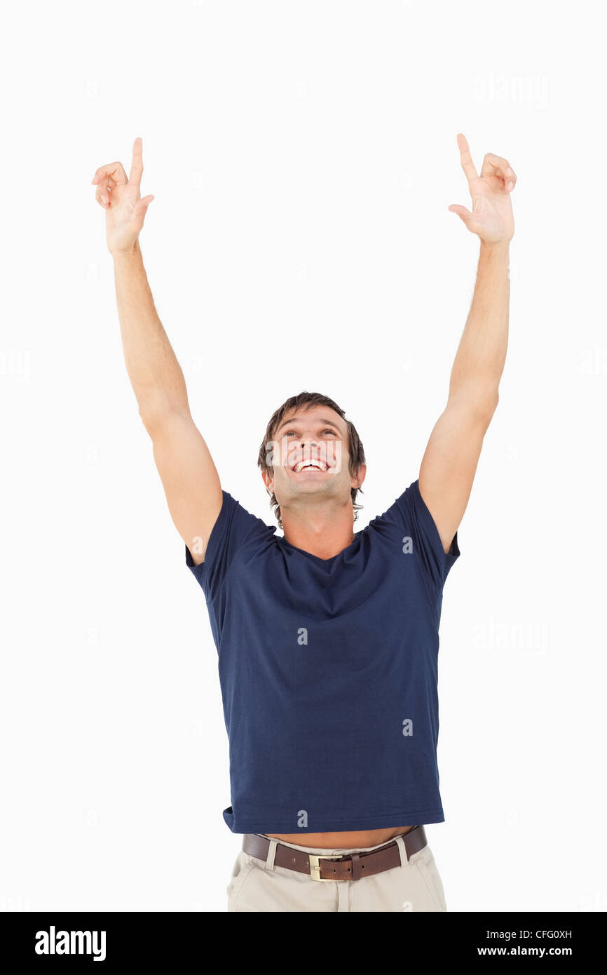 Smiling man showing his happiness by raising his arms above his head ...