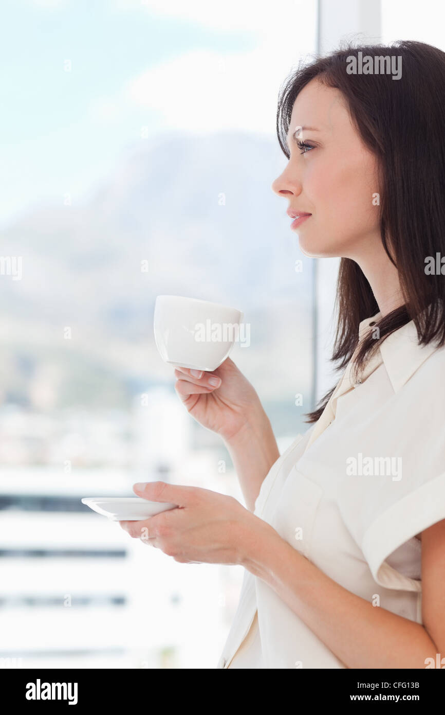 Woman looking out a window while drinking tea Stock Photo - Alamy