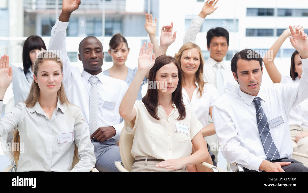 Colleagues raising their hands while sitting together Stock Photo - Alamy
