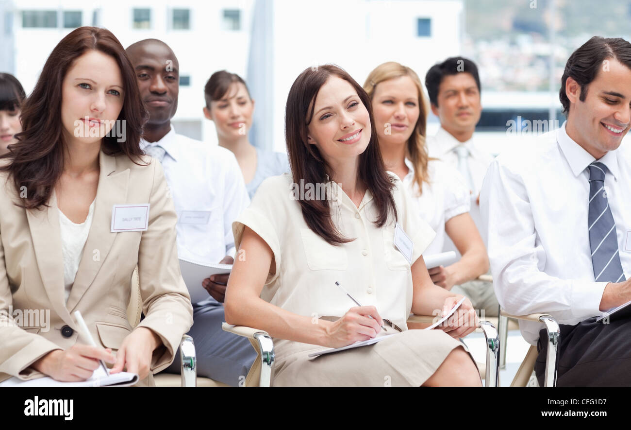 Colleagues smiling as they write notes while sitting together Stock ...