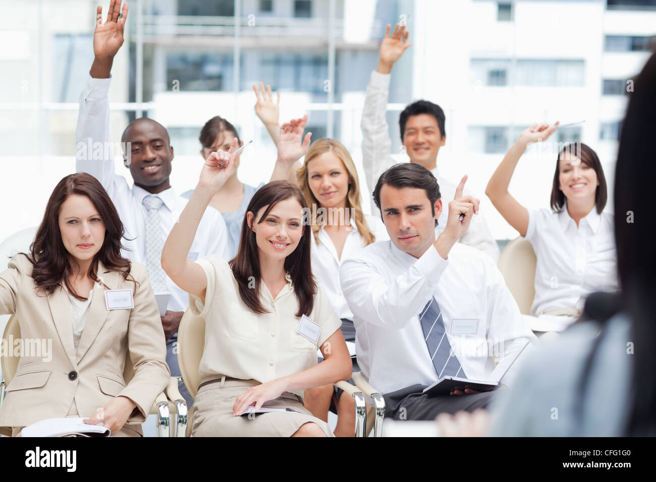Colleagues raising their hands while watching a speaker Stock Photo - Alamy