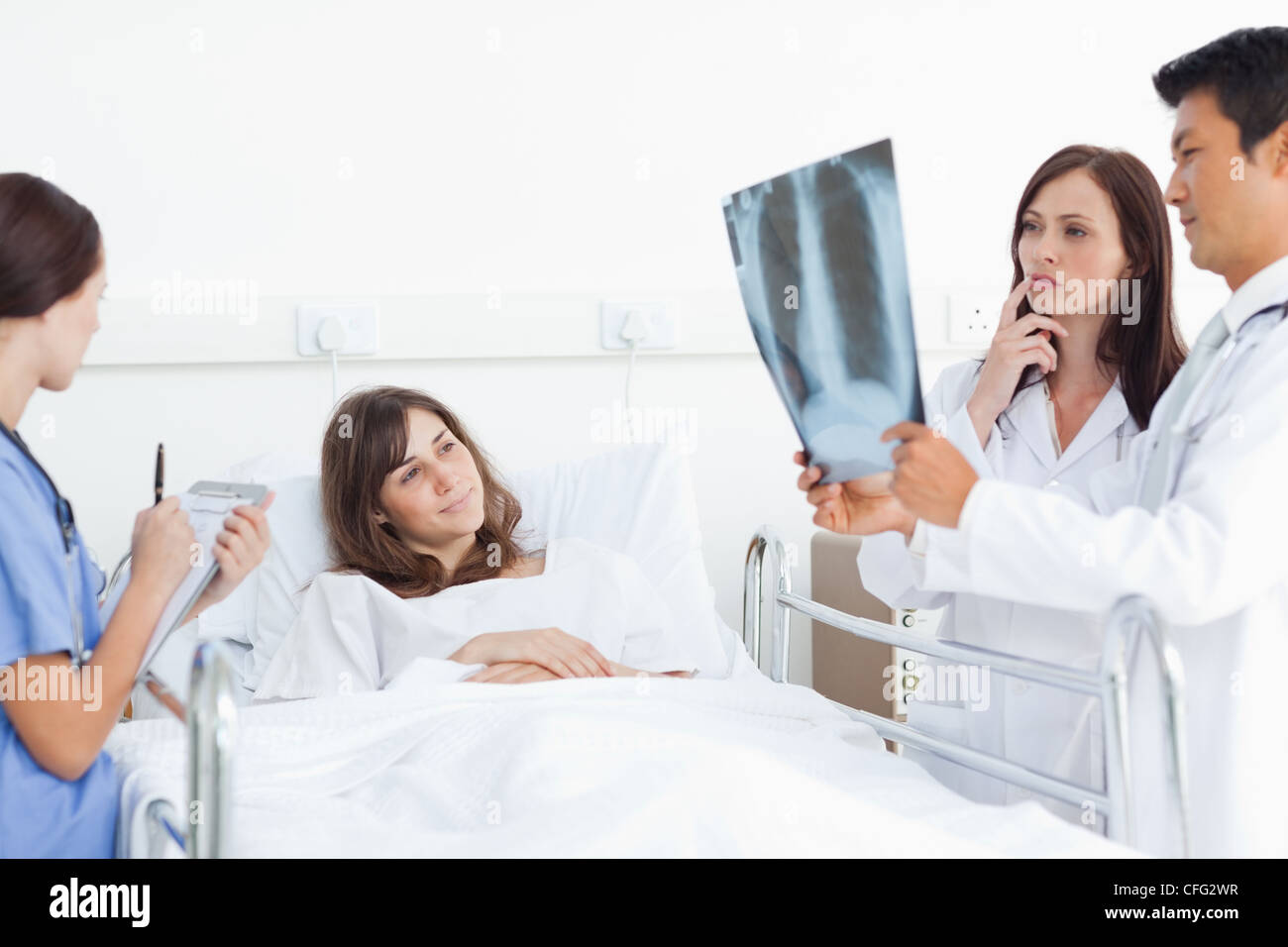 Doctors looking at an x-ray scan while a patient is watching them Stock ...