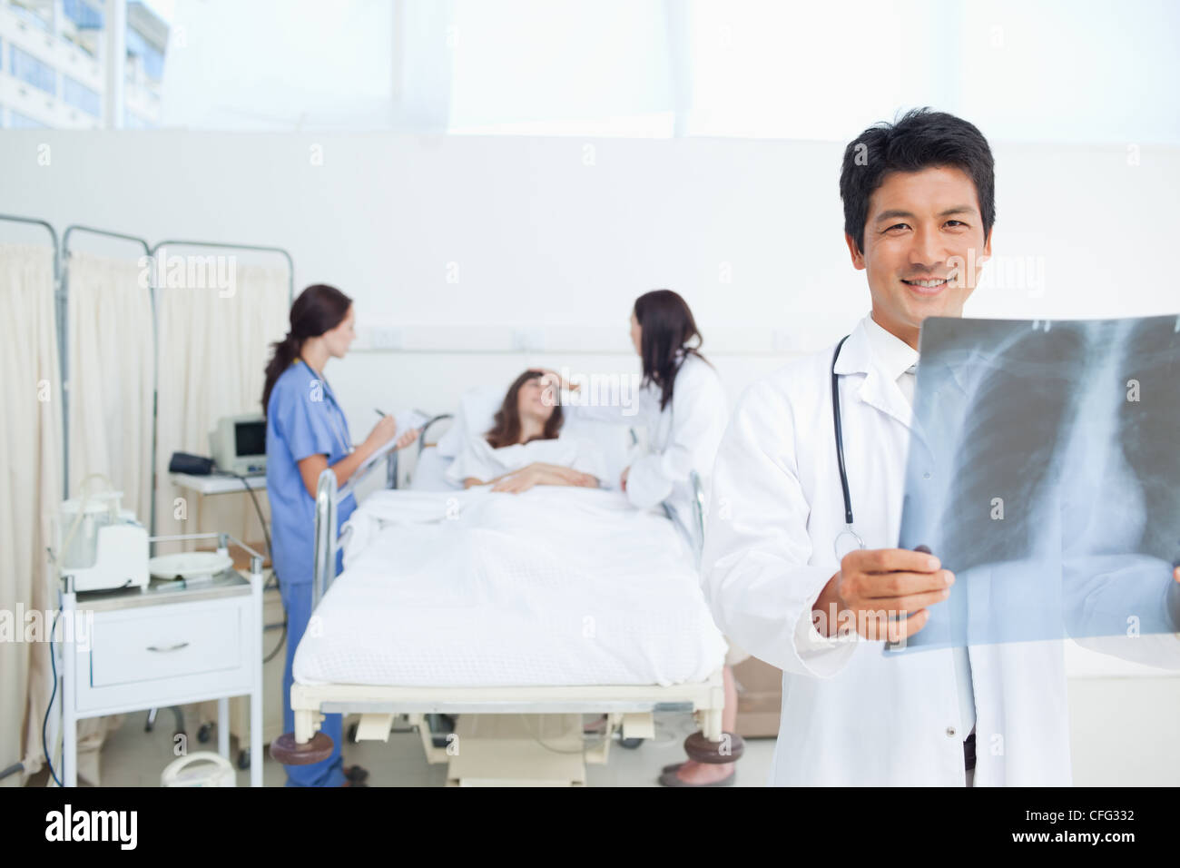 Doctor smiling as he holds an x-ray scan while his colleagues are ...