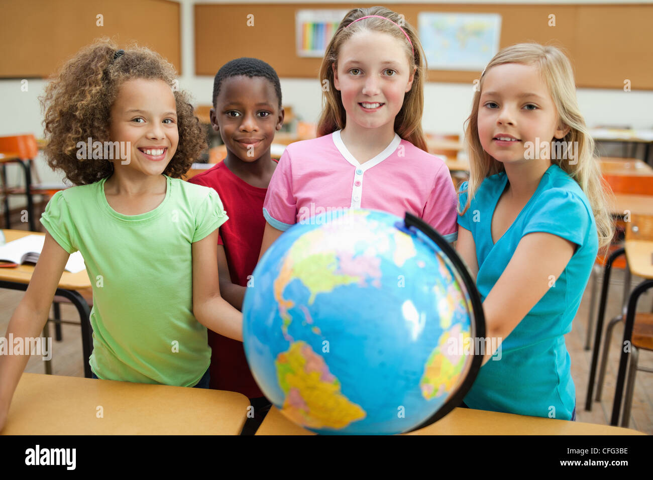 Students standing behind globe Stock Photo - Alamy