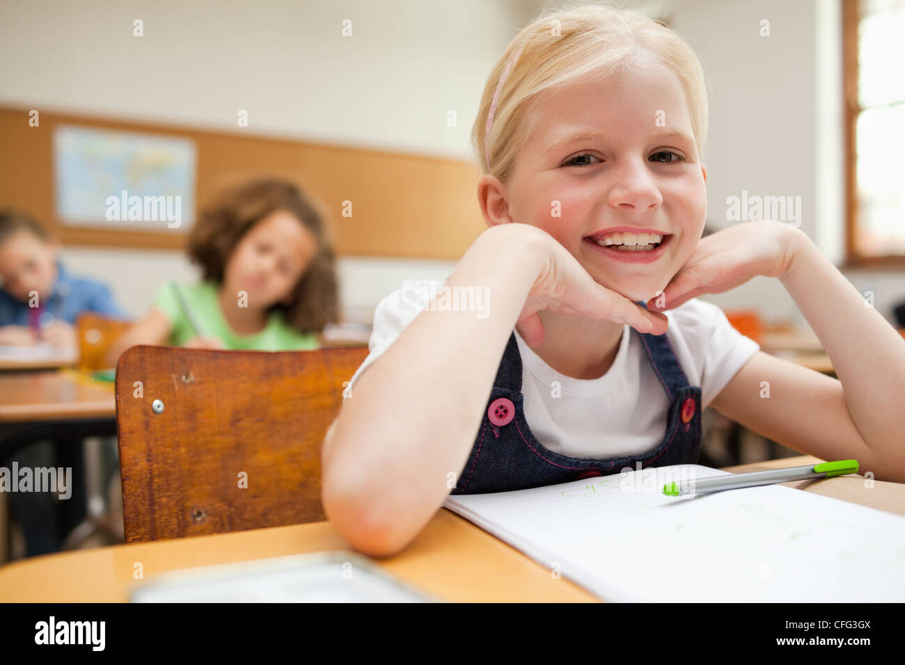 Smiling girl sitting at desk in class Stock Photo - Alamy