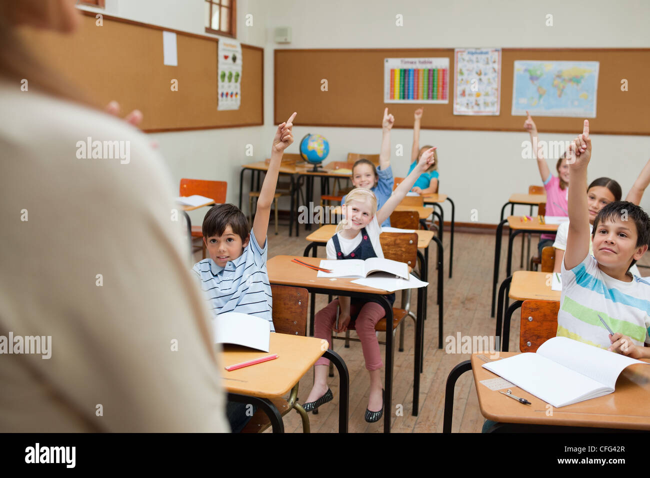 Students with arms raised in class Stock Photo - Alamy