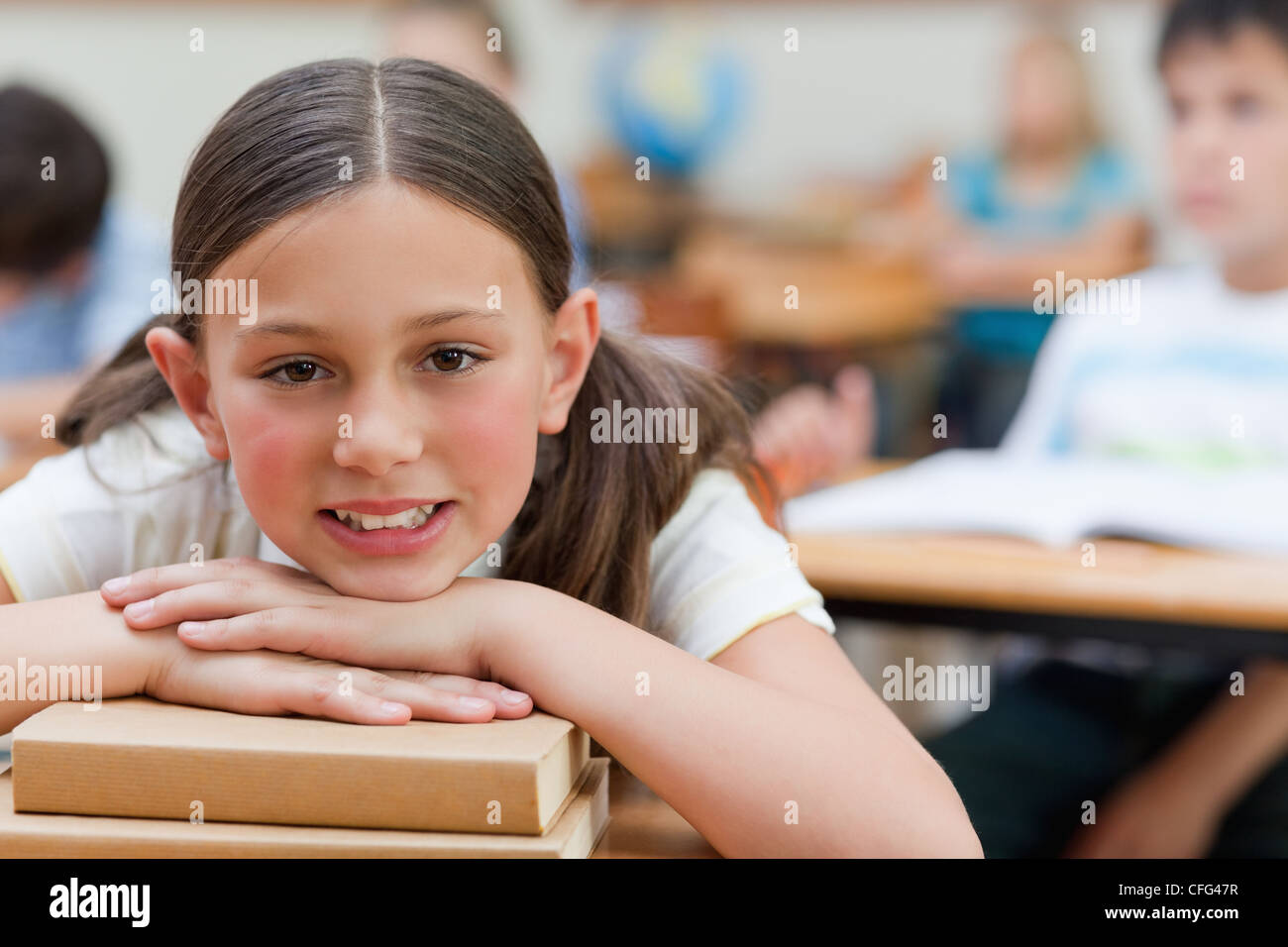 Primary student leaning on pile of books Stock Photo - Alamy