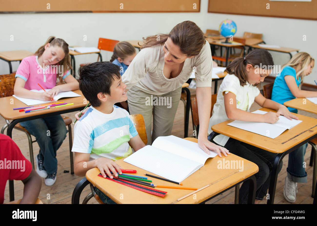 Helpful teacher next to one of her students Stock Photo - Alamy