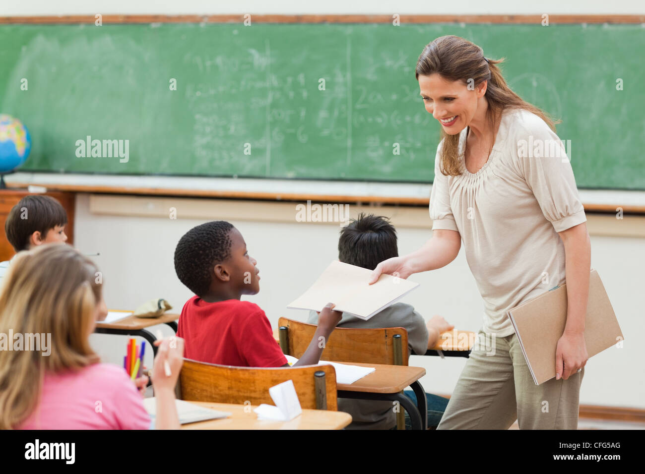 Teacher collecting her students exercise books Stock Photo - Alamy