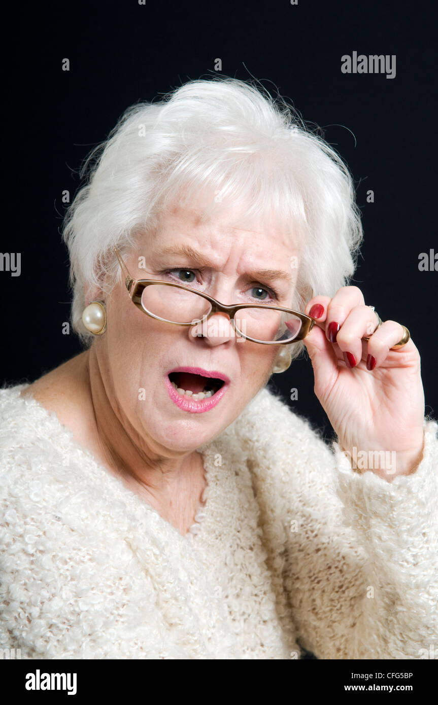 Senior lady with a surprised look on face peering over glasses taken ...