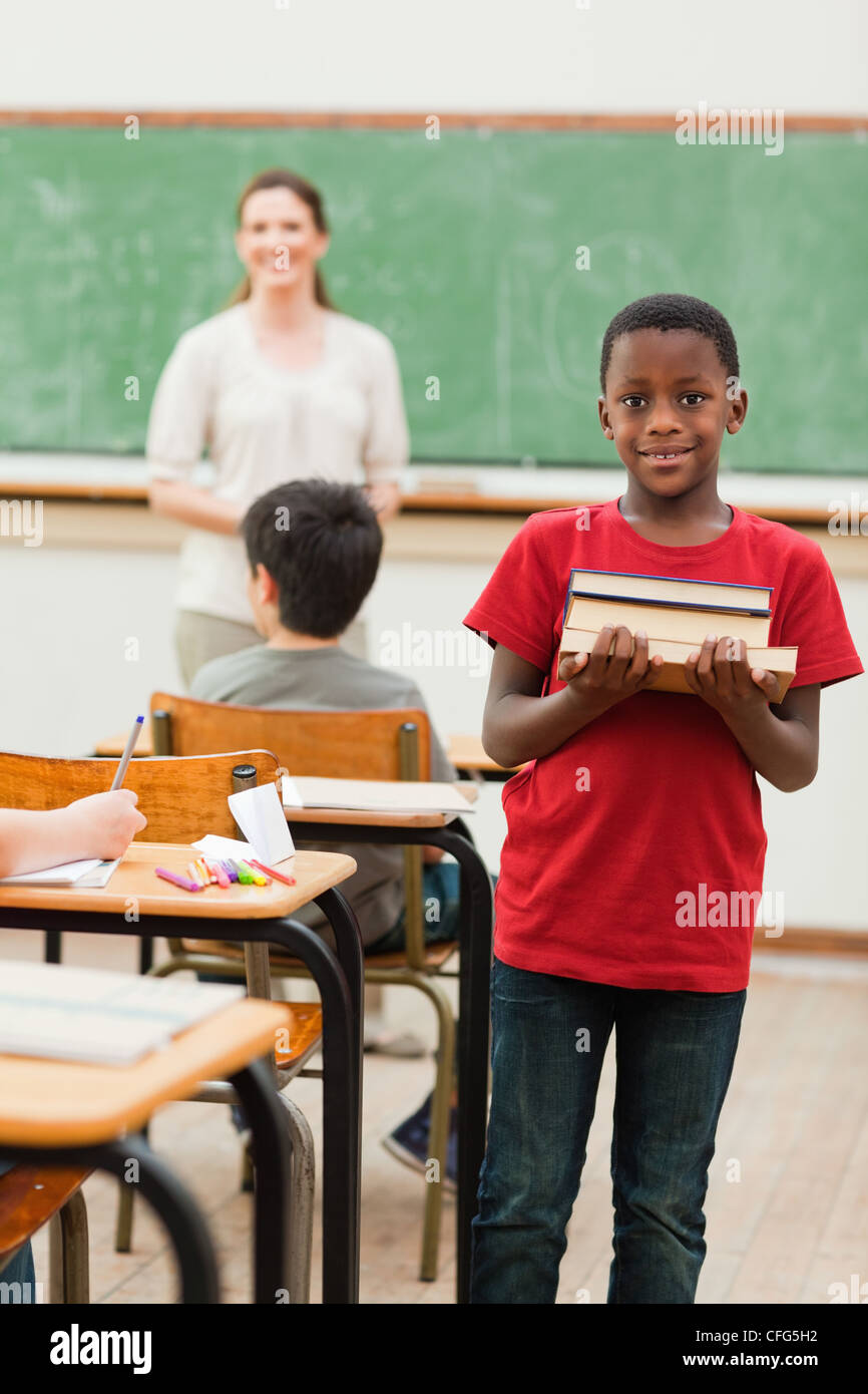 Smiling student holding stack of books Stock Photo - Alamy
