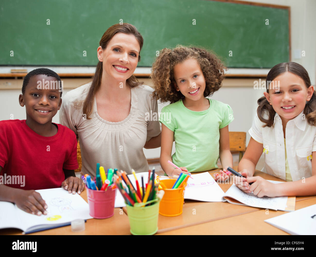 Smiling teacher sitting together with her students Stock Photo - Alamy