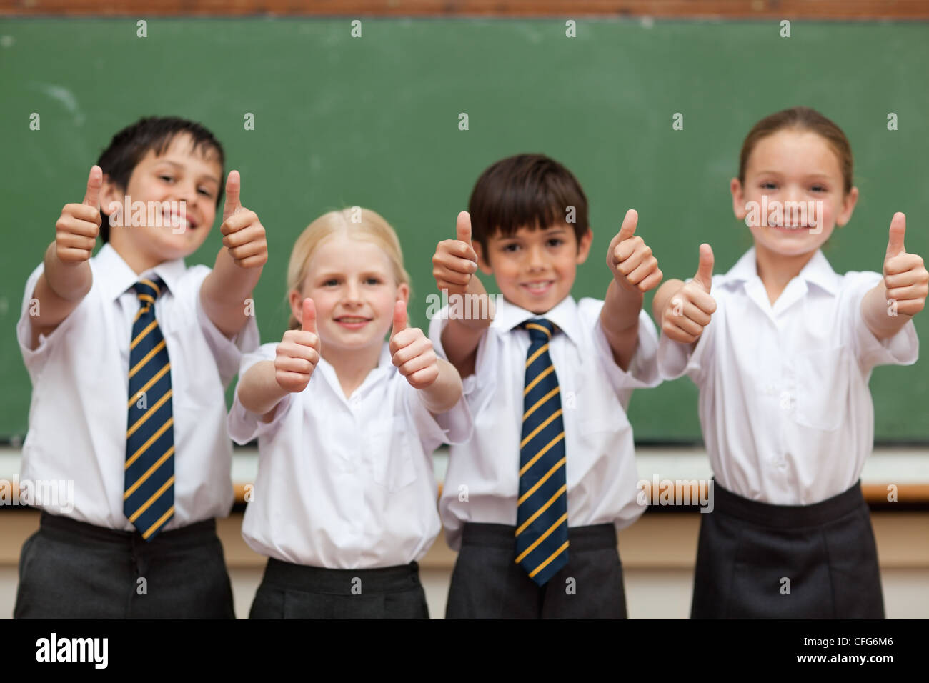 Smiling students in school uniforms giving thumbs up Stock Photo - Alamy