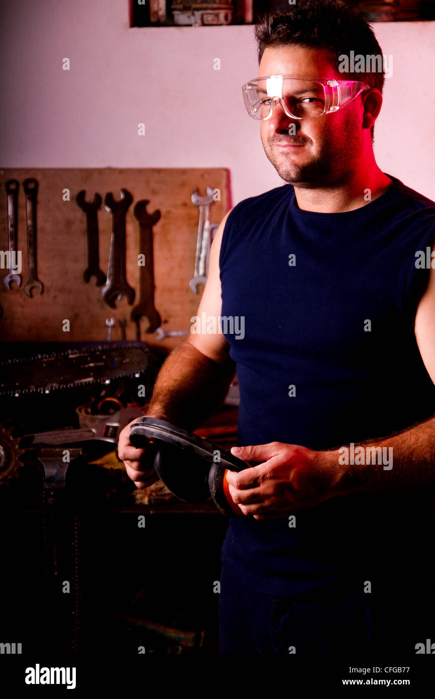 View of a garage mechanic man smiling and holding some protective ...