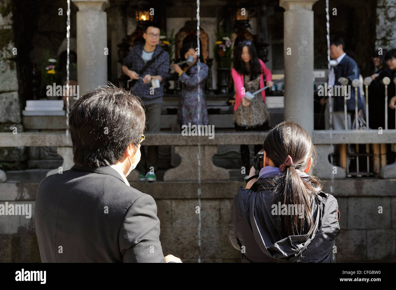 Japanese woman photographing people scooping holy water at Kiyomizu ...