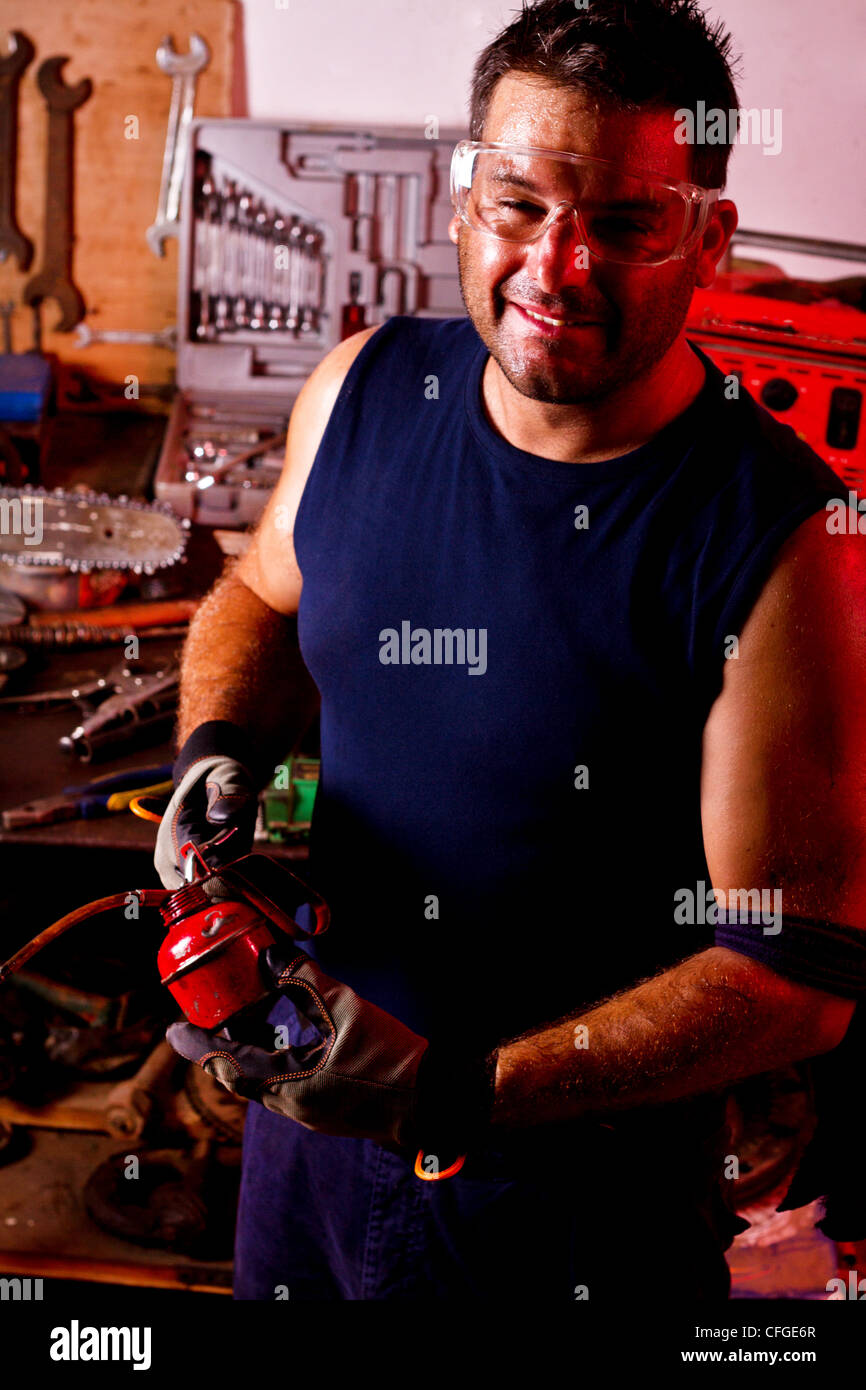 View of a happy garage mechanic man holding a oil can Stock Photo - Alamy