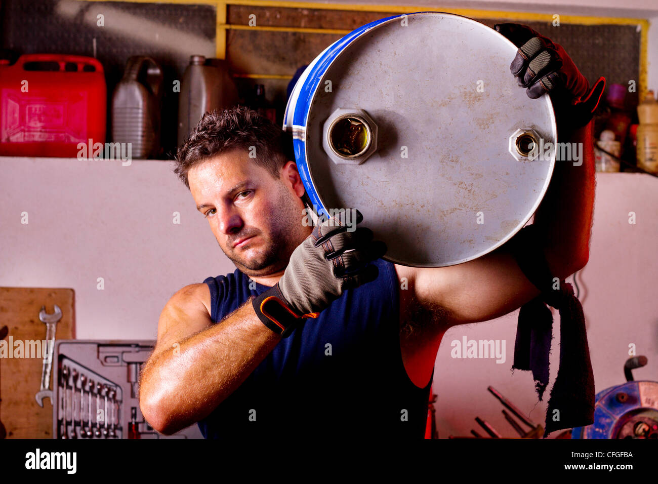 View of a happy garage mechanic man holding an oil barrel Stock Photo ...