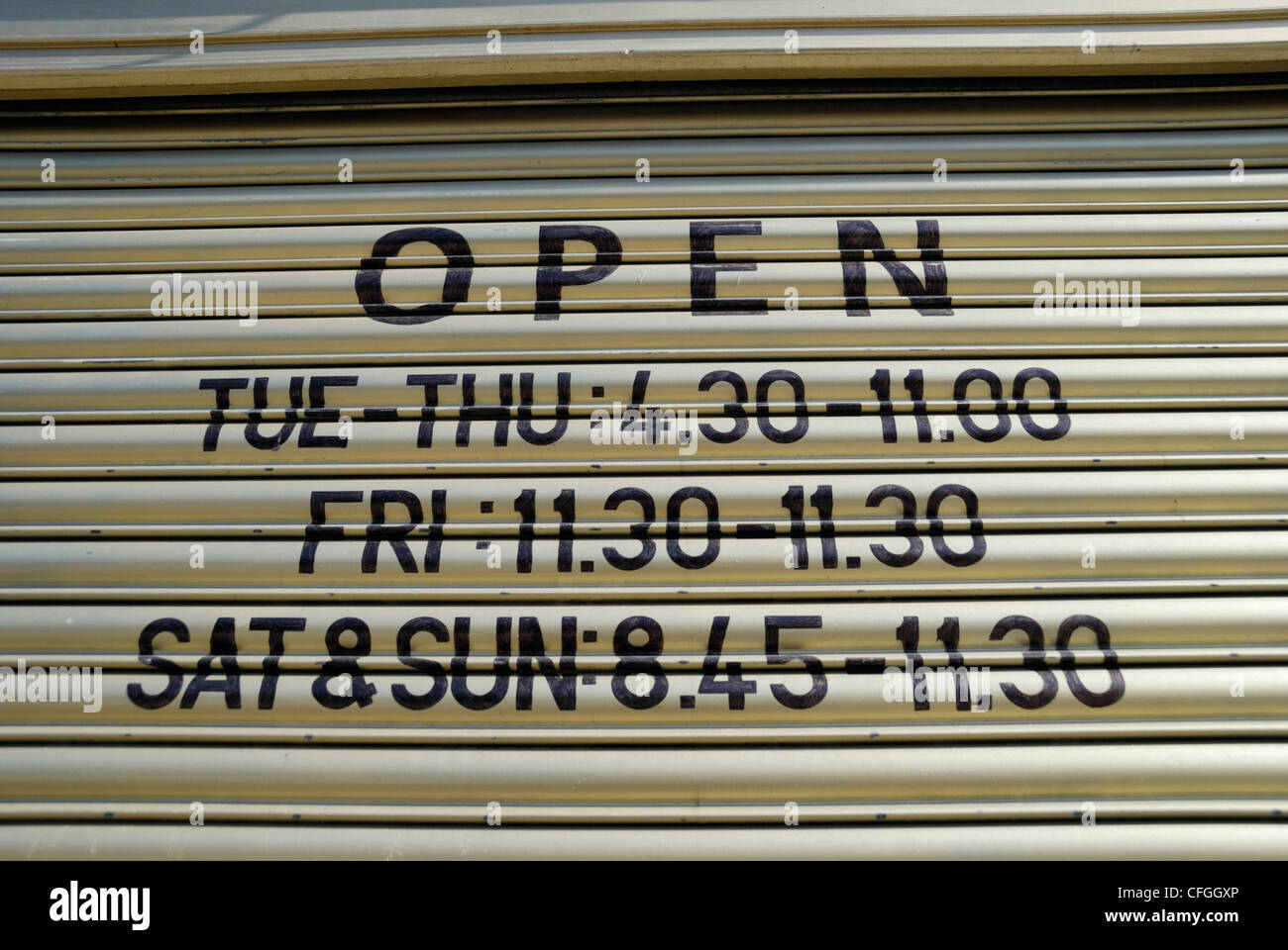 Shop opening hours displayed on a metal shutter Stock Photo - Alamy