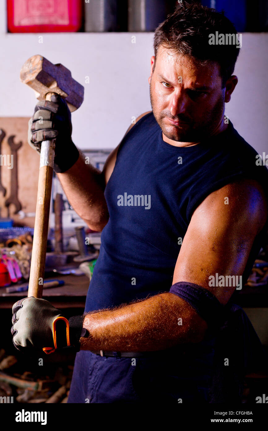 View of a garage mechanic man holding a big hammer Stock Photo - Alamy