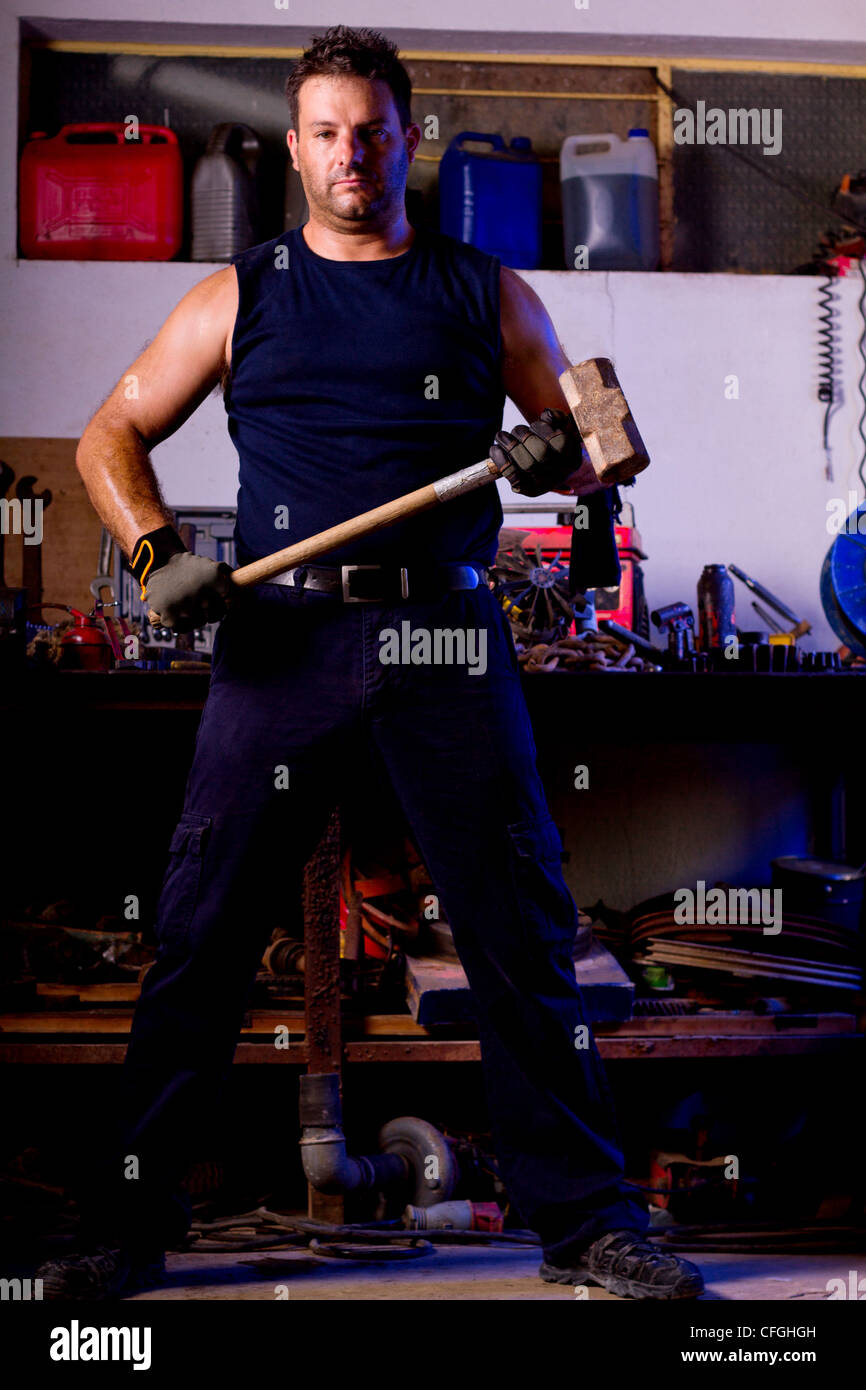 View of a garage mechanic man holding a big hammer Stock Photo - Alamy