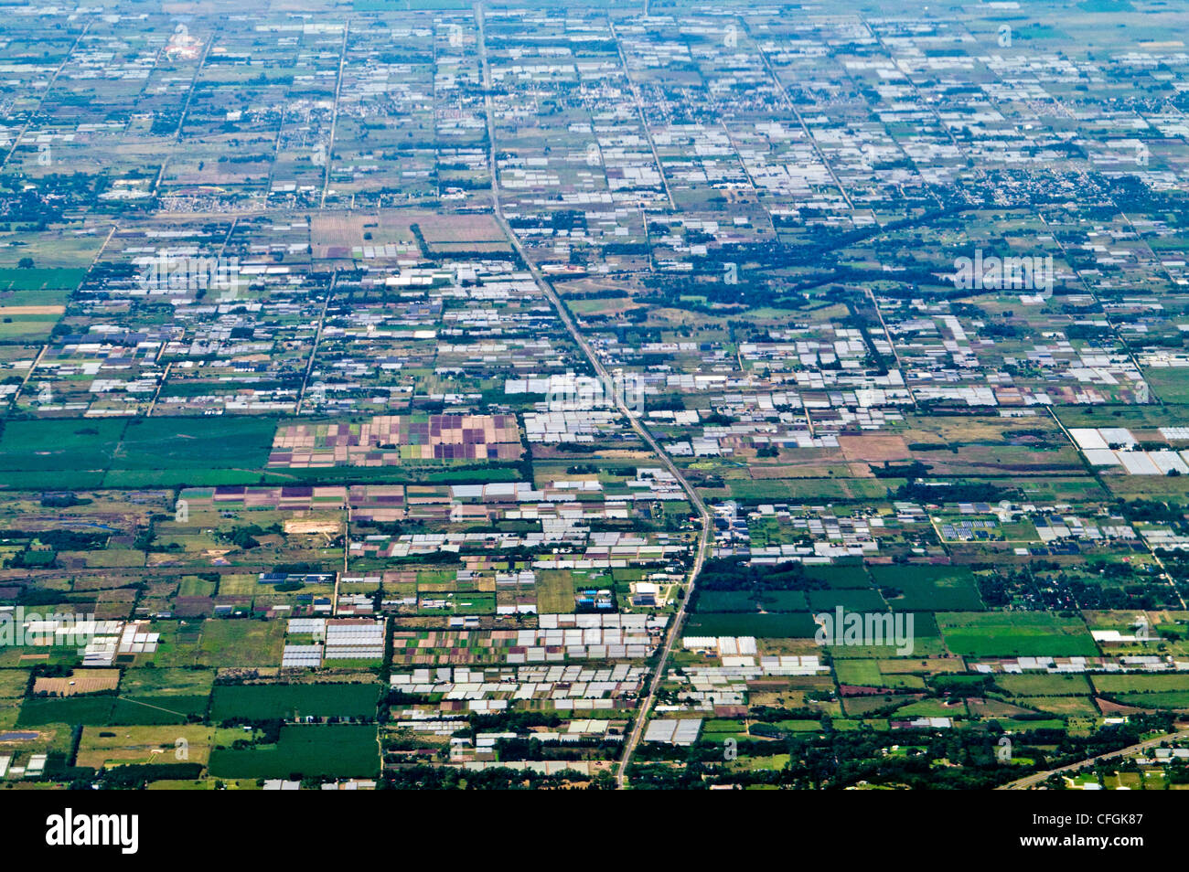 A patchwork of farmland paddocks, factories and warehouses on a plain ...