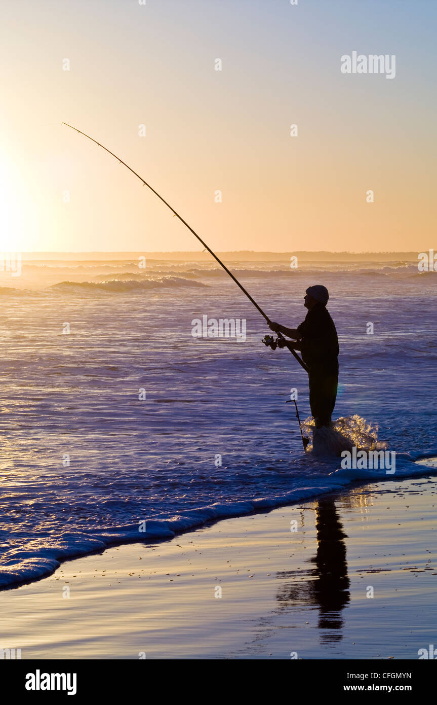 Fishermen try to hook a fish in the waves with long surf fishing rods ...
