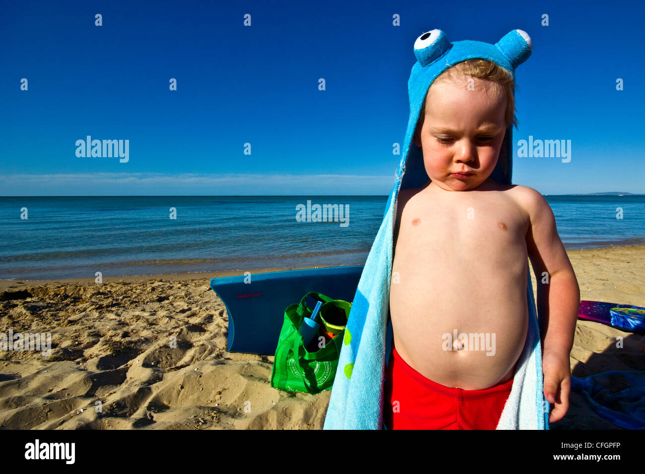 A cheeky boy pokes out his tummy whilst wrapped in an octopus towel ...