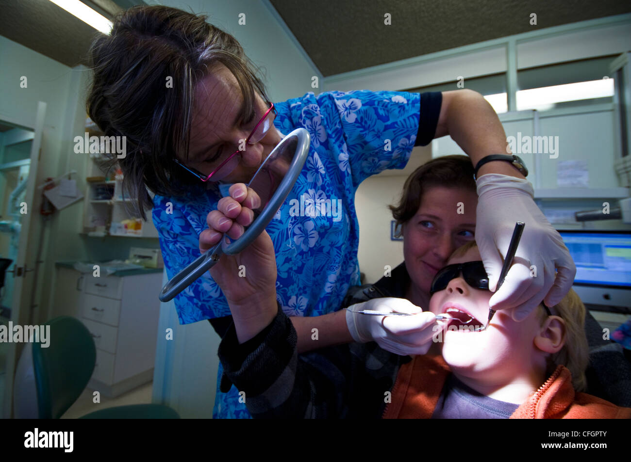 A dentist examines a small boy's baby teeth during his first check-up ...