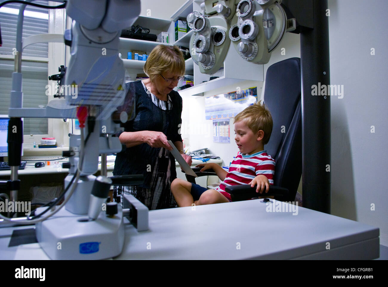 An optometrist gives a small boy his first eye chart examination Stock ...