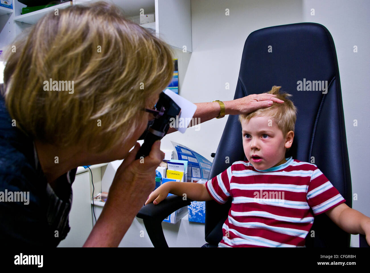 A children's optometrist gives a small boy his first eye examination ...