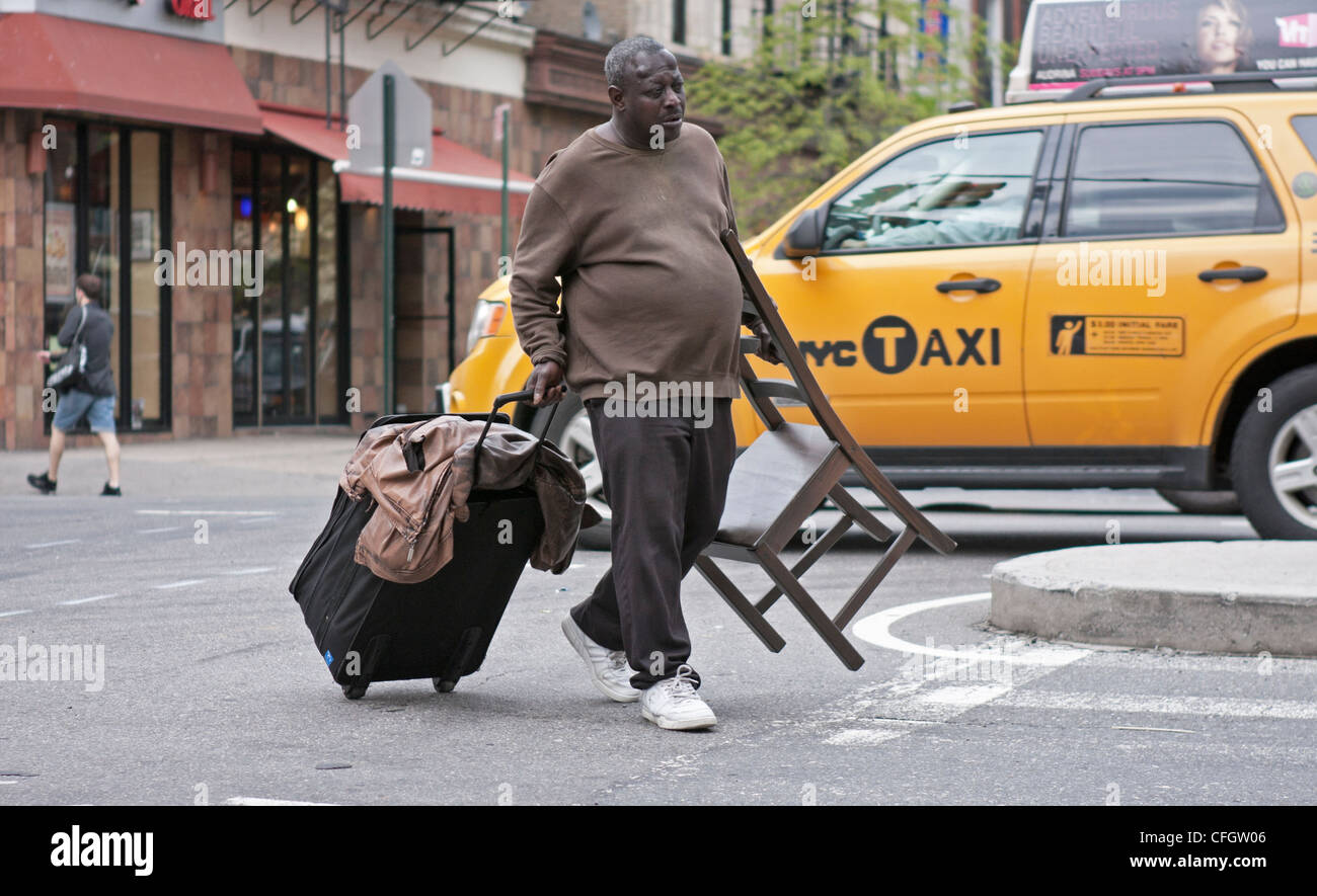 A man carrying a chair walks across a street in New York City Stock ...