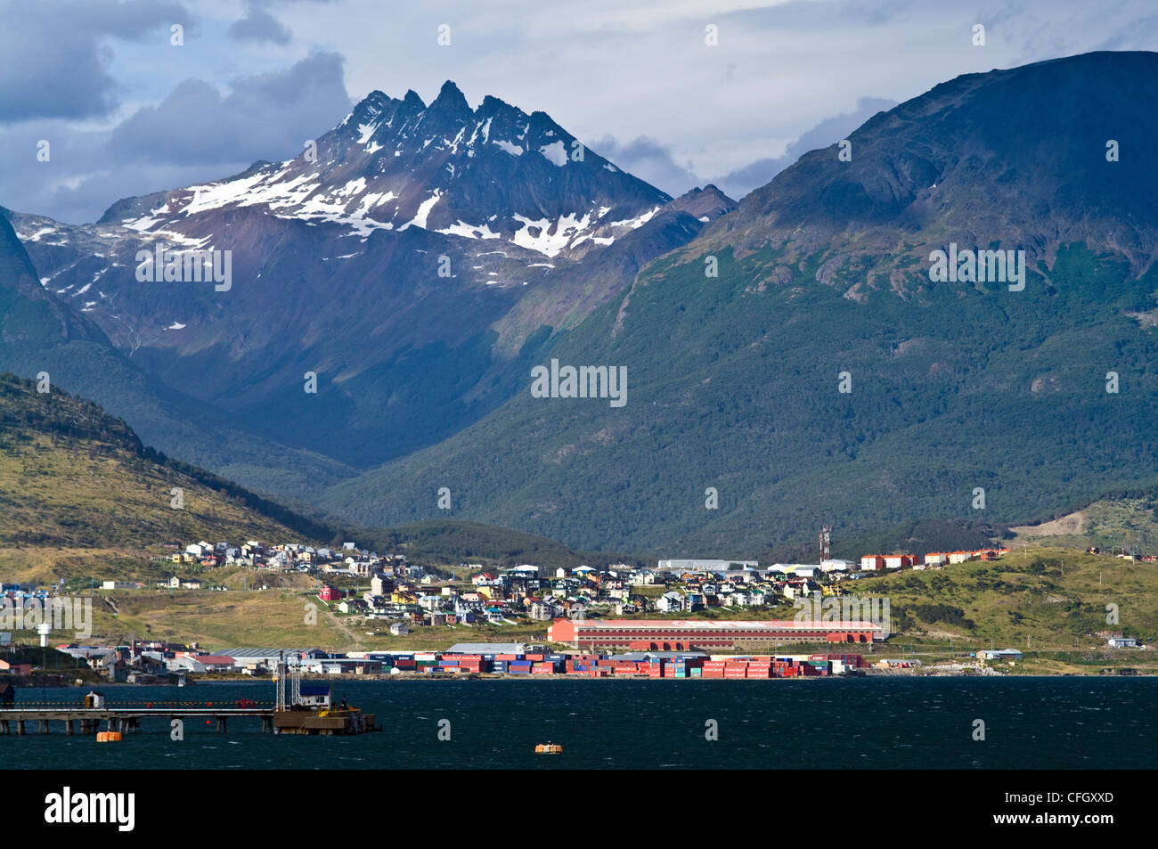 Shipping containers and warehouses line a port beneath an alpine city ...