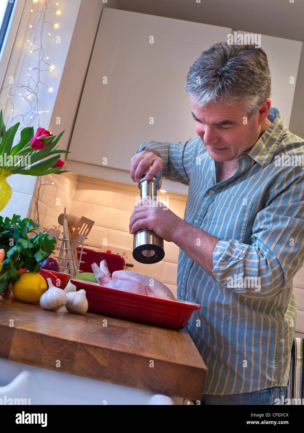 Man in contemporary kitchen seasoning and preparing a meal of roast ...