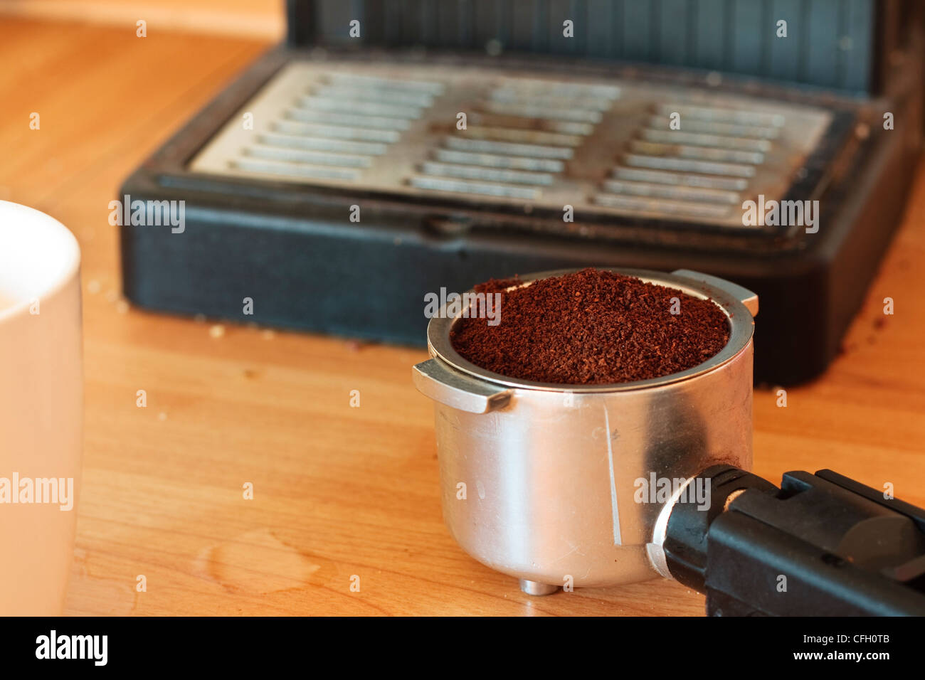 An espresso machine portafilter, filled with ground coffee ready to be ...