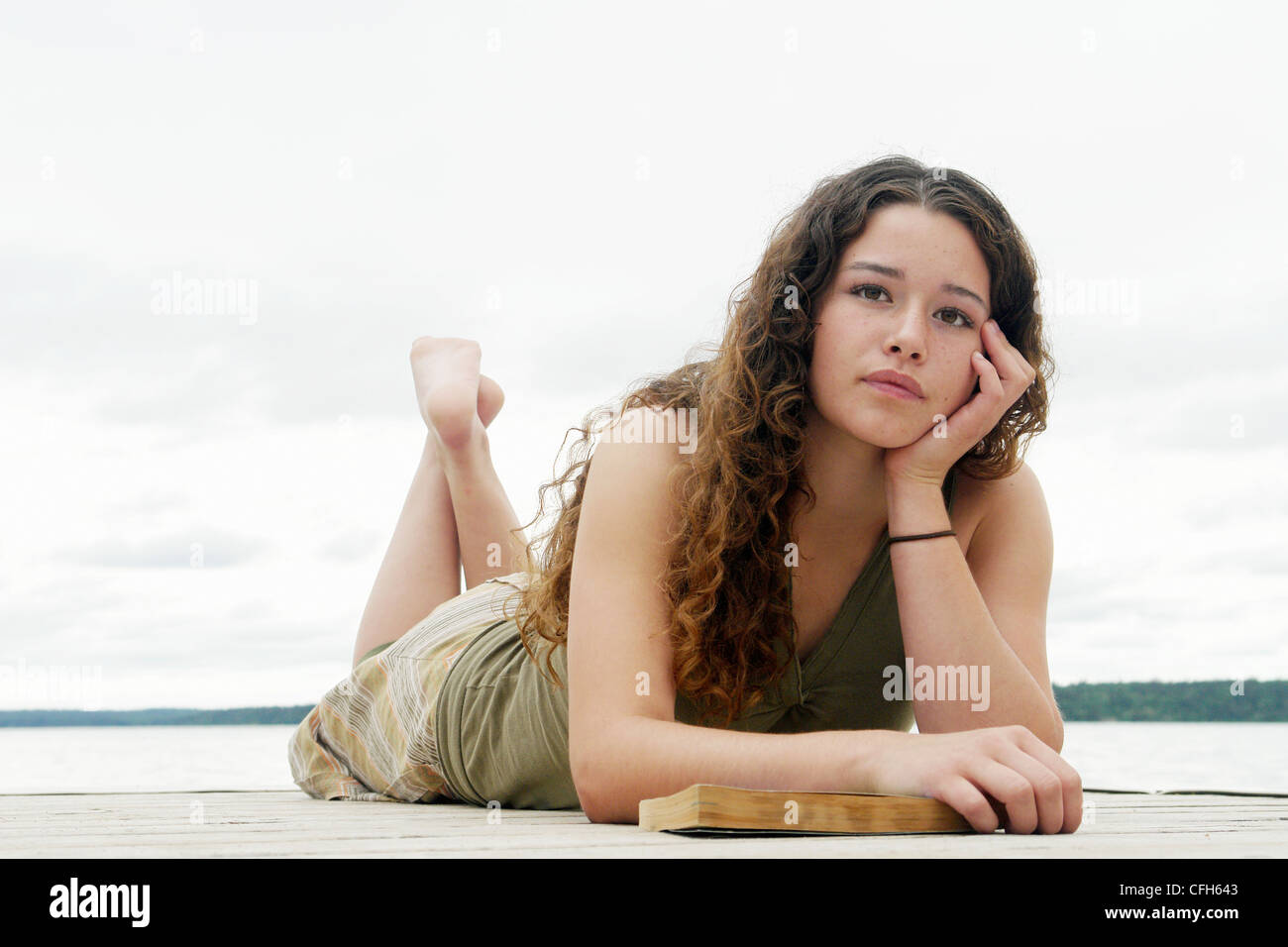 Teen Laying on Dock with a Book Stock Photo - Alamy