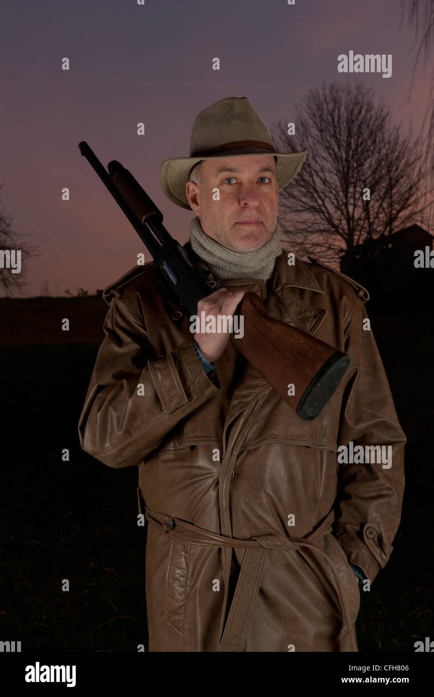 man with cowboy hat, long leather coat and riot gun at night Stock ...