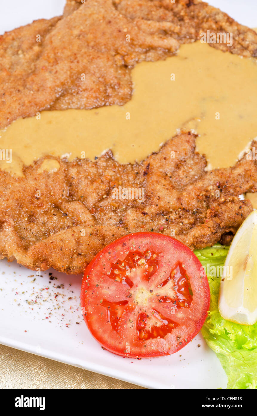 Delicious Schnitzel with lemon, tomato, lettuce and sauce Stock Photo ...