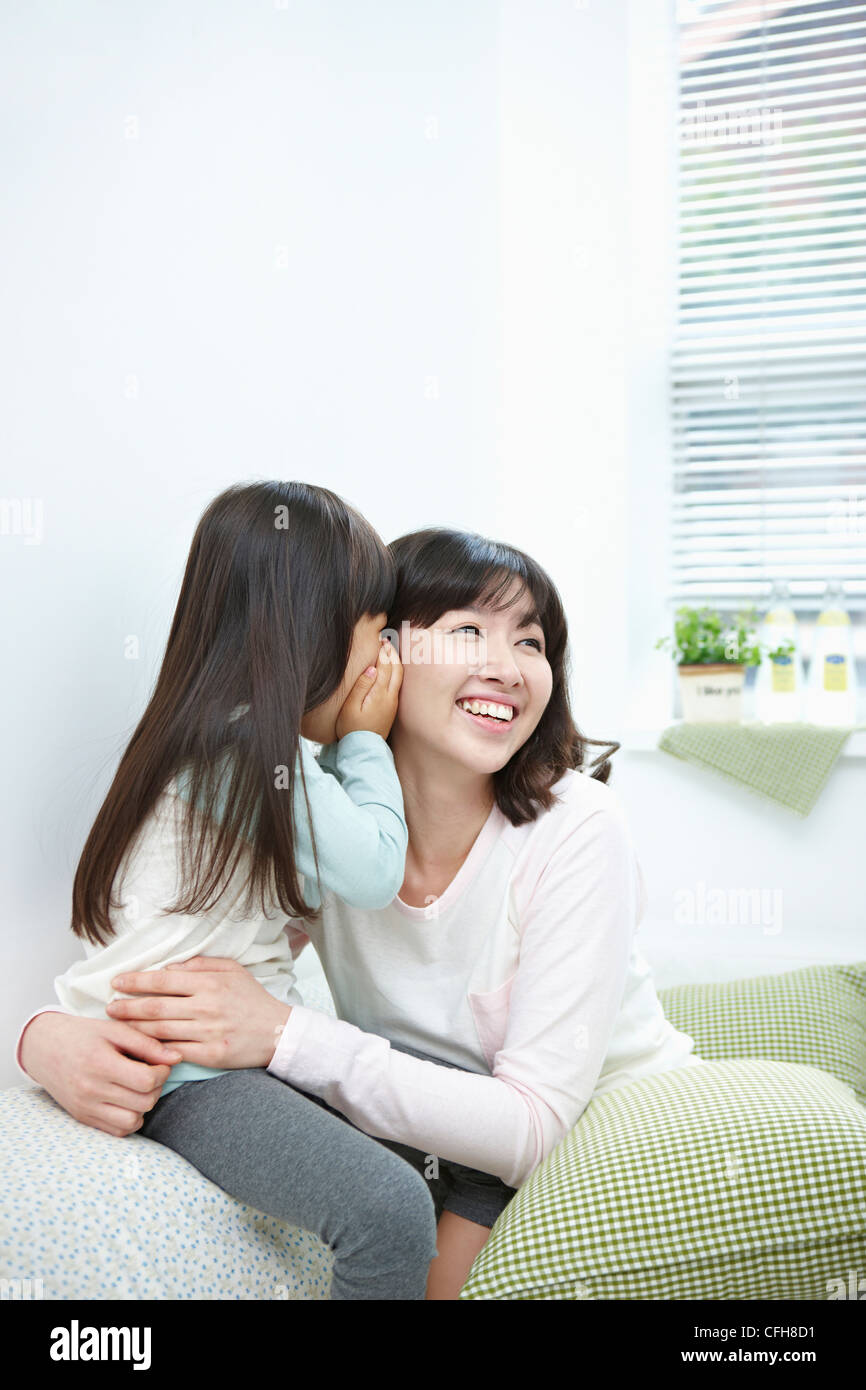 The girl whispering in woman's ear Stock Photo - Alamy