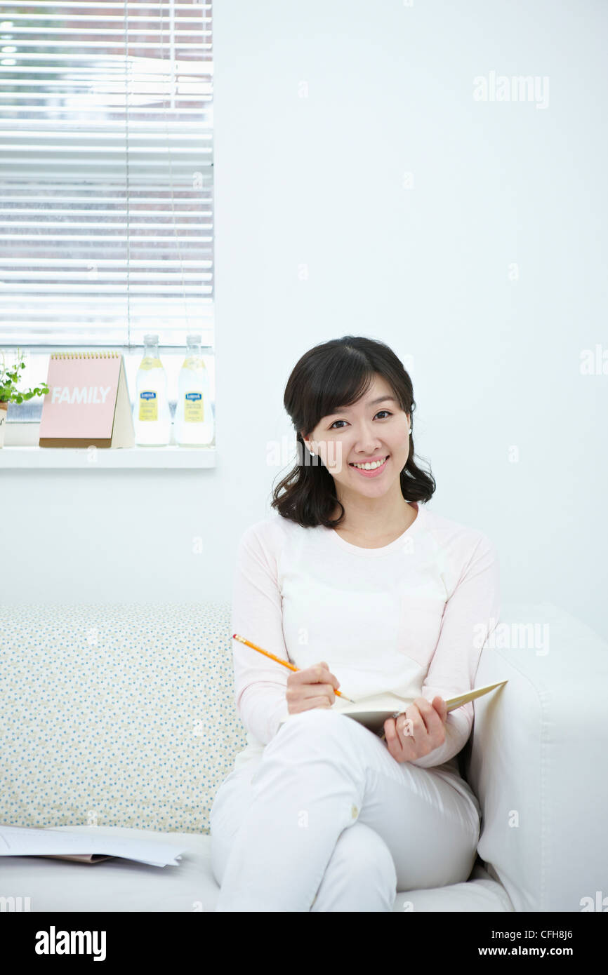 The smiling woman holding the pencil and notebook Stock Photo - Alamy