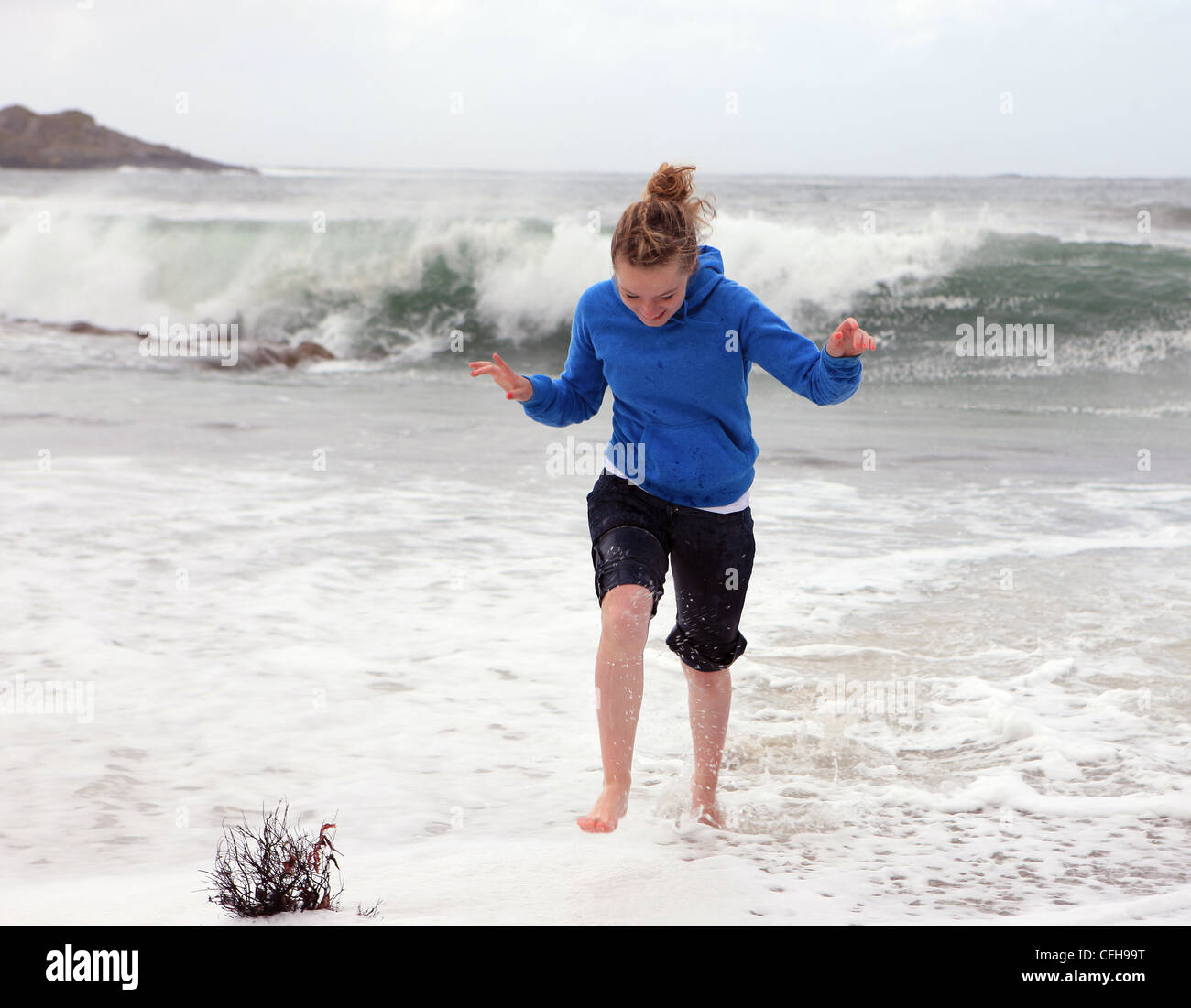 Girl running way from a large wave in the sea on the Isle of Mull Stock ...