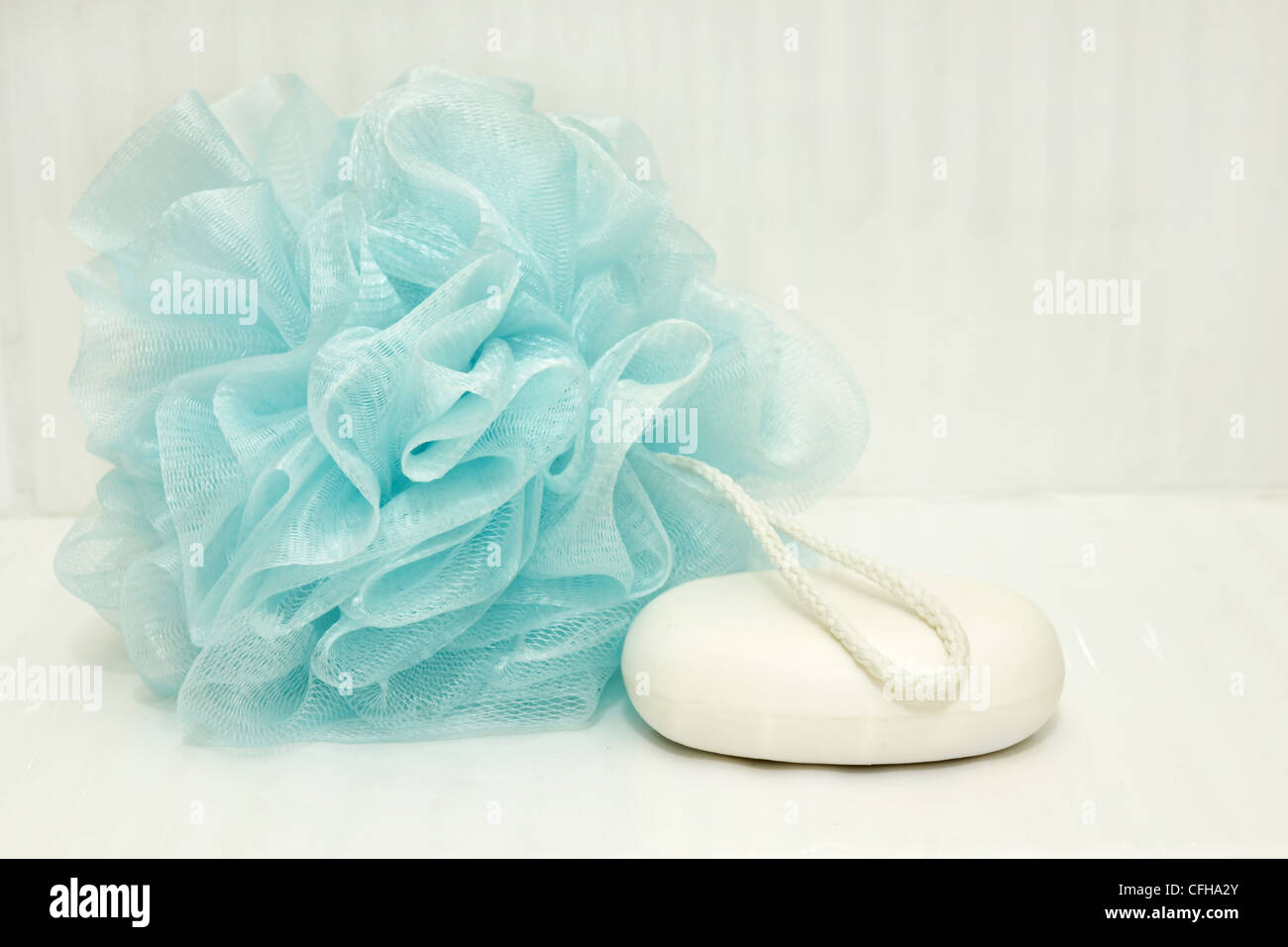 Clean and fresh spa concept: light blue bath puff with bar of soap on ...